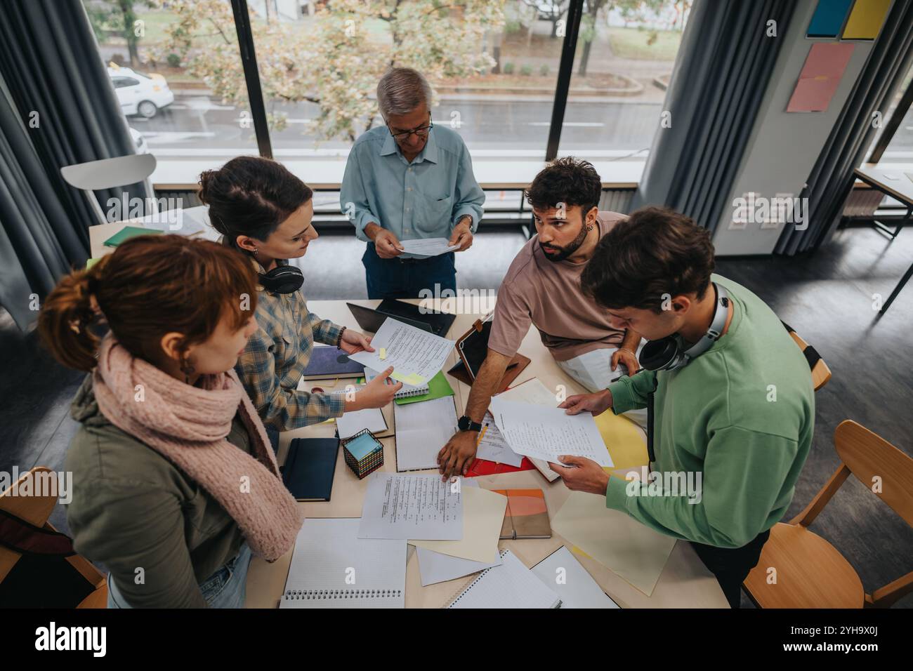College students collaborating with professor in modern classroom ...
