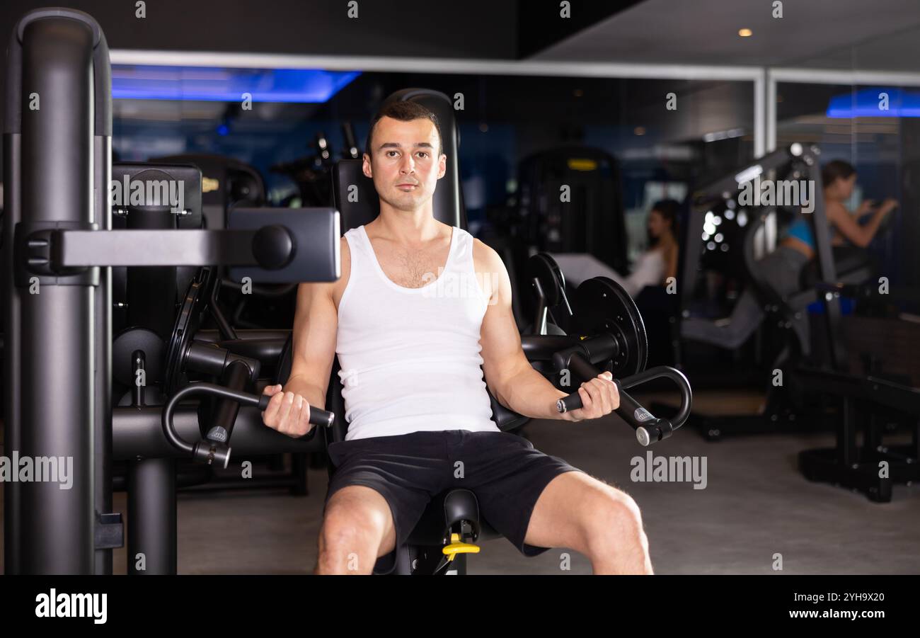 Slender athletic man work out muscles of arms and shoulders on ...