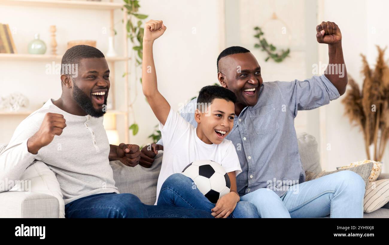 Excited black grandfather, dad and son cheering favorite football team ...