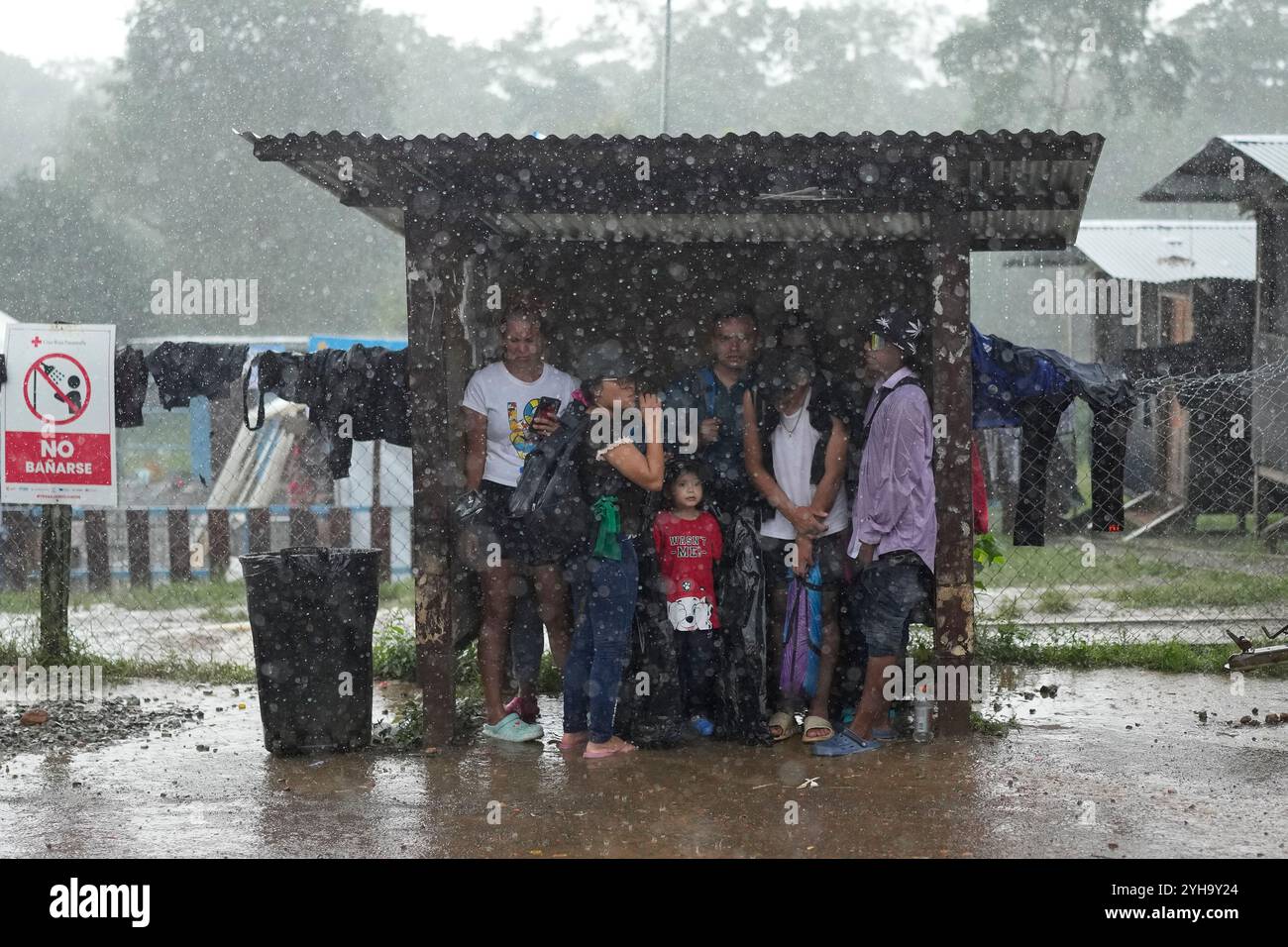 Migrants wait outside an immigration post after trekking across the ...