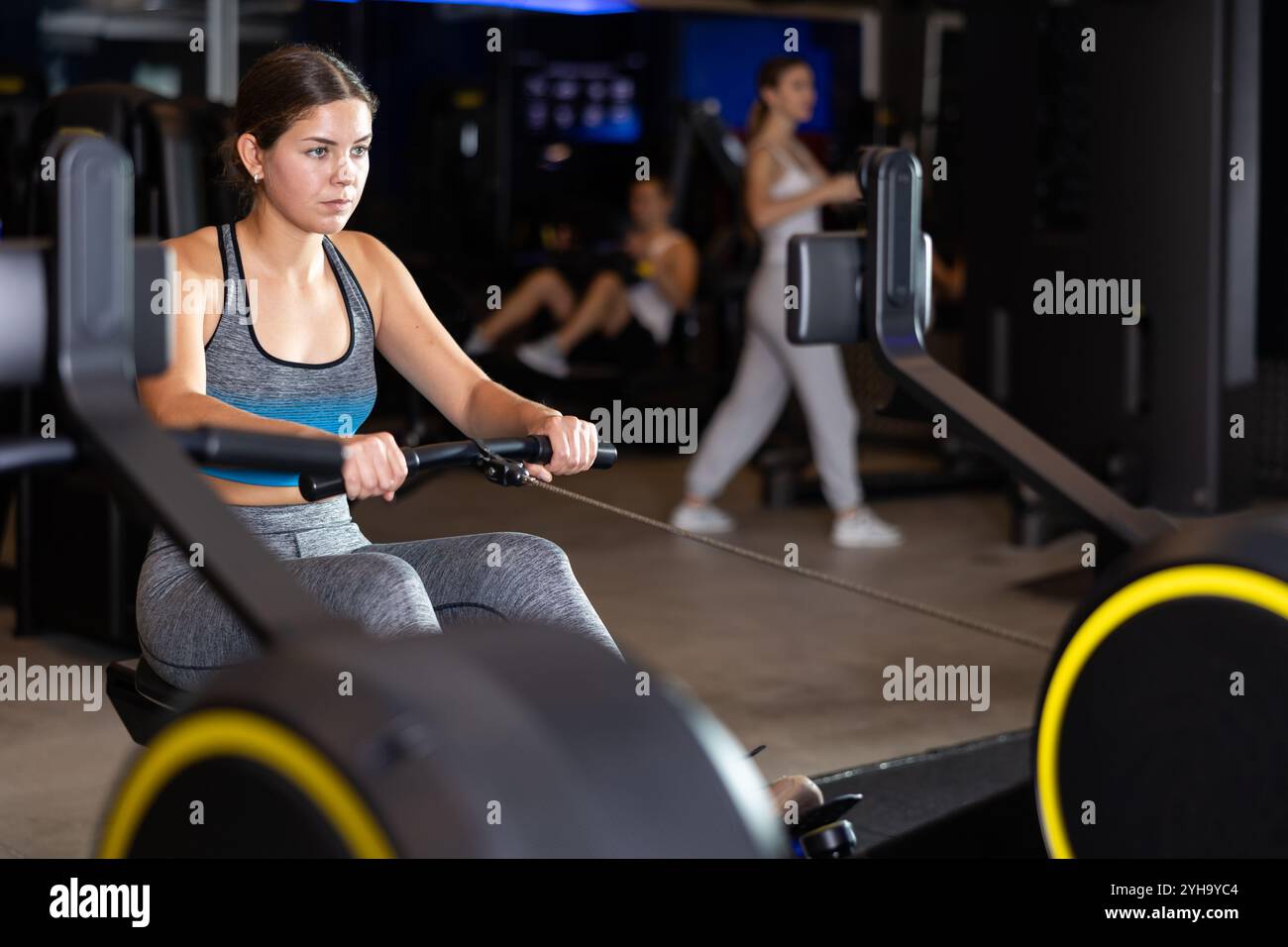 Sportive young girl training on cable row machine in gym Stock Photo ...