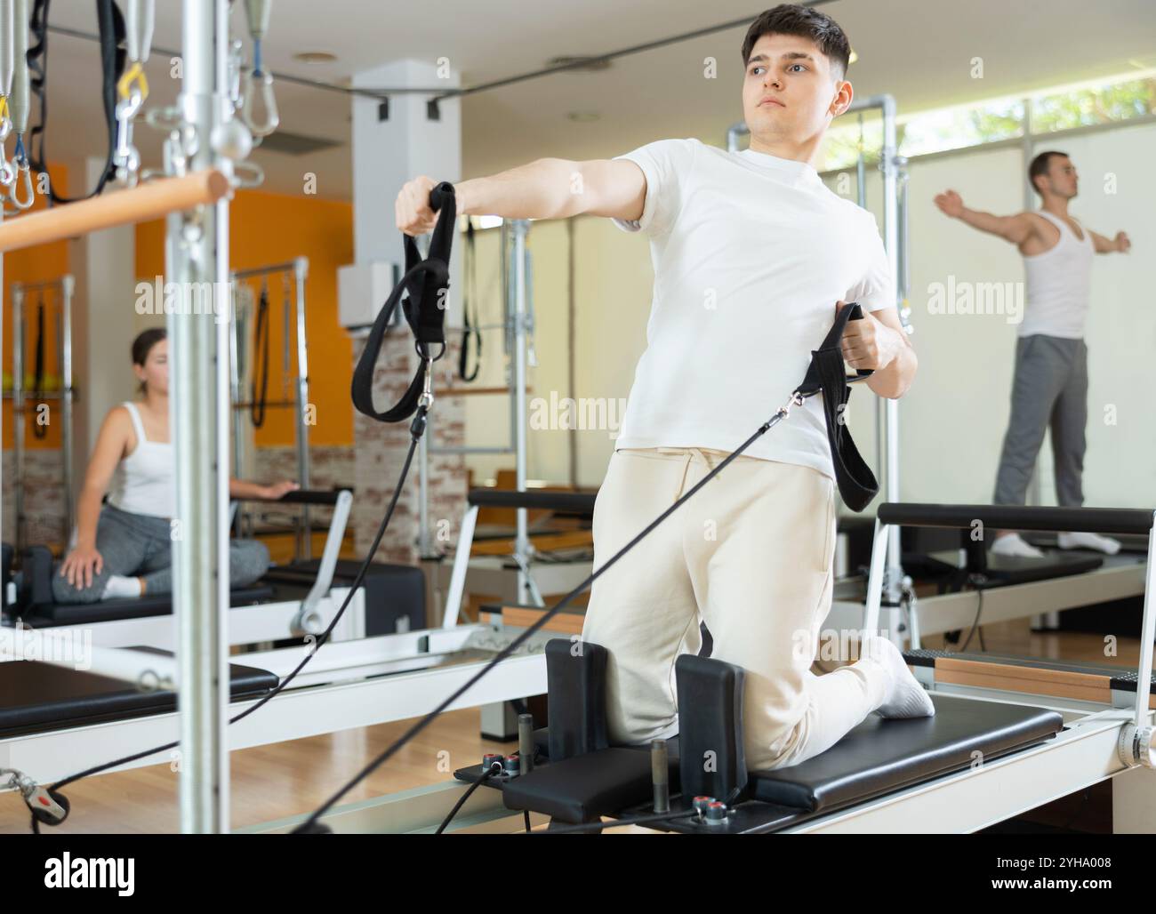 Guy doing exercises with straps in arms on Pilates reformer Stock Photo ...