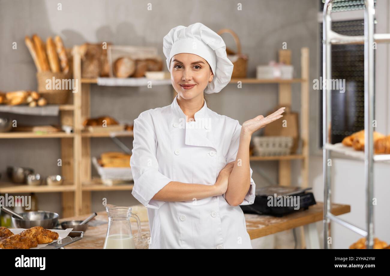 Smiling female baker making welcoming gesture in bakery Stock Photo - Alamy