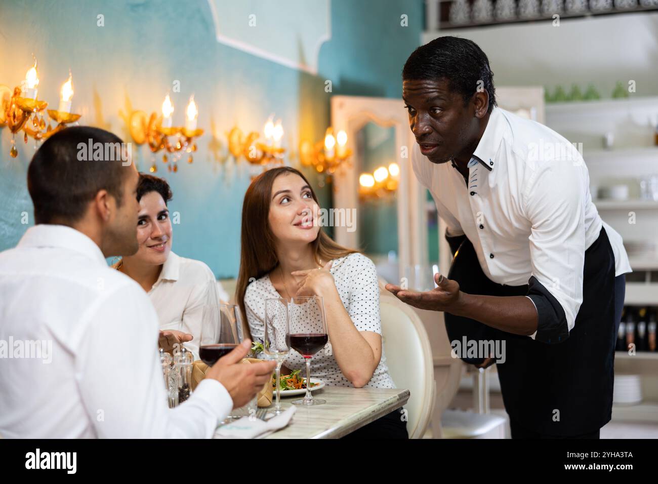 Waiter serving two women at the restaurant Stock Photo - Alamy