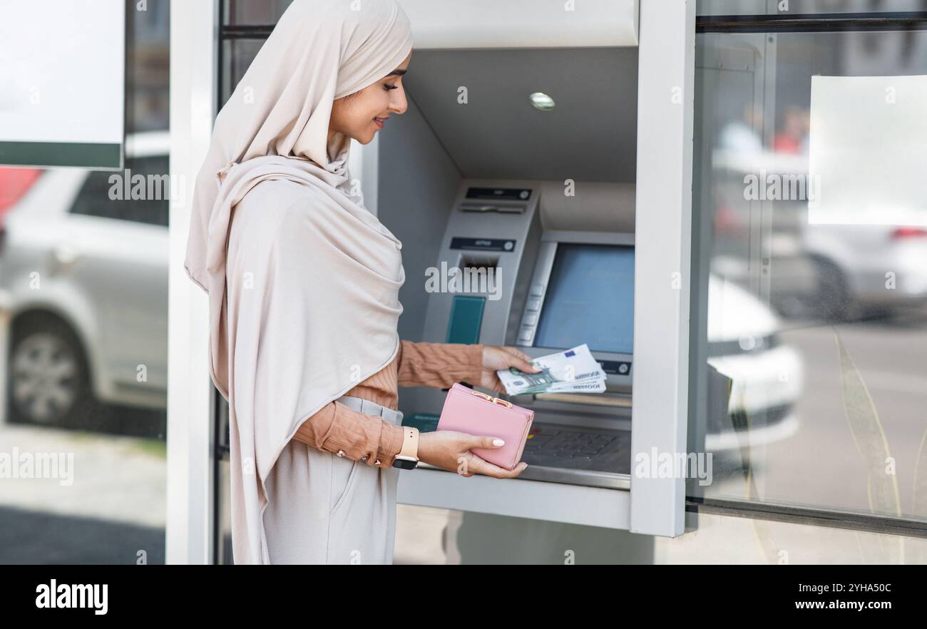 Concentrated cute young arab woman holds money withdrawn from ATM Stock ...