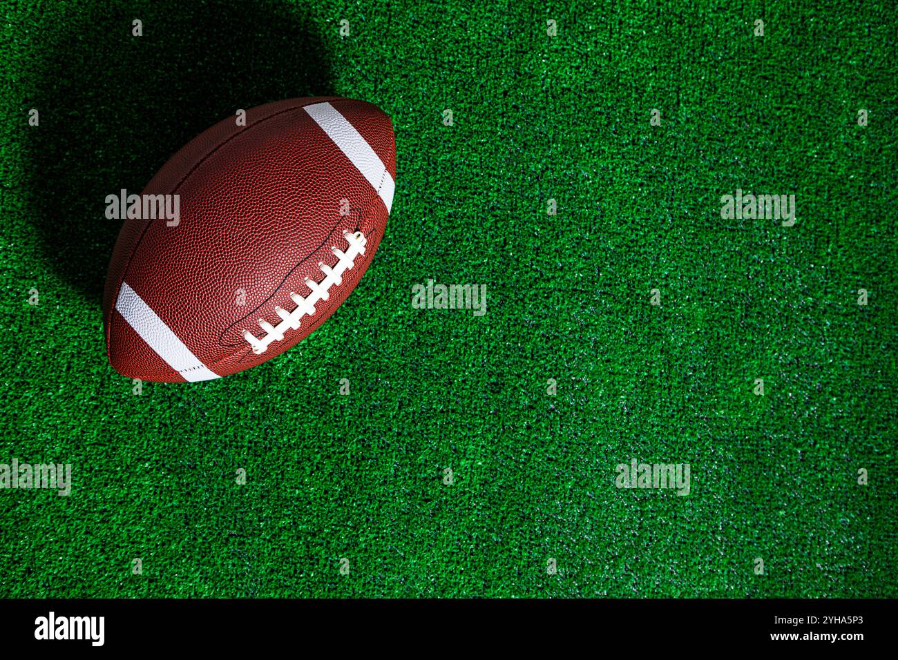 An American football ball isolated on the grass tilted in a corner ...