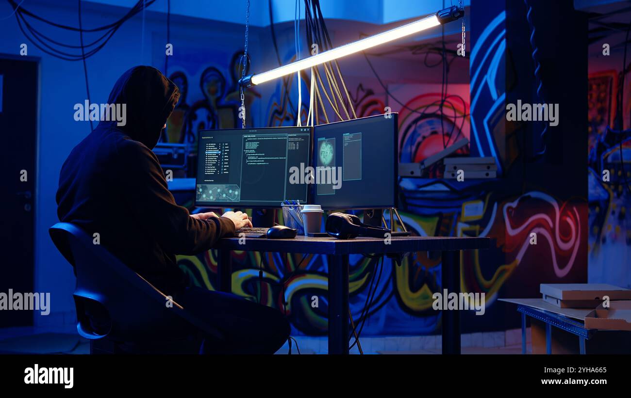 Hooded man in underground hideaway listening and breaking into computer ...