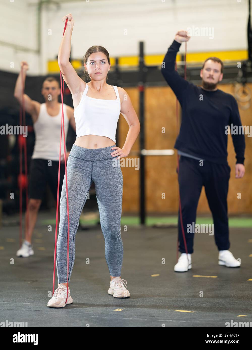 Sporty girl exercising with resistance band loop during group training ...