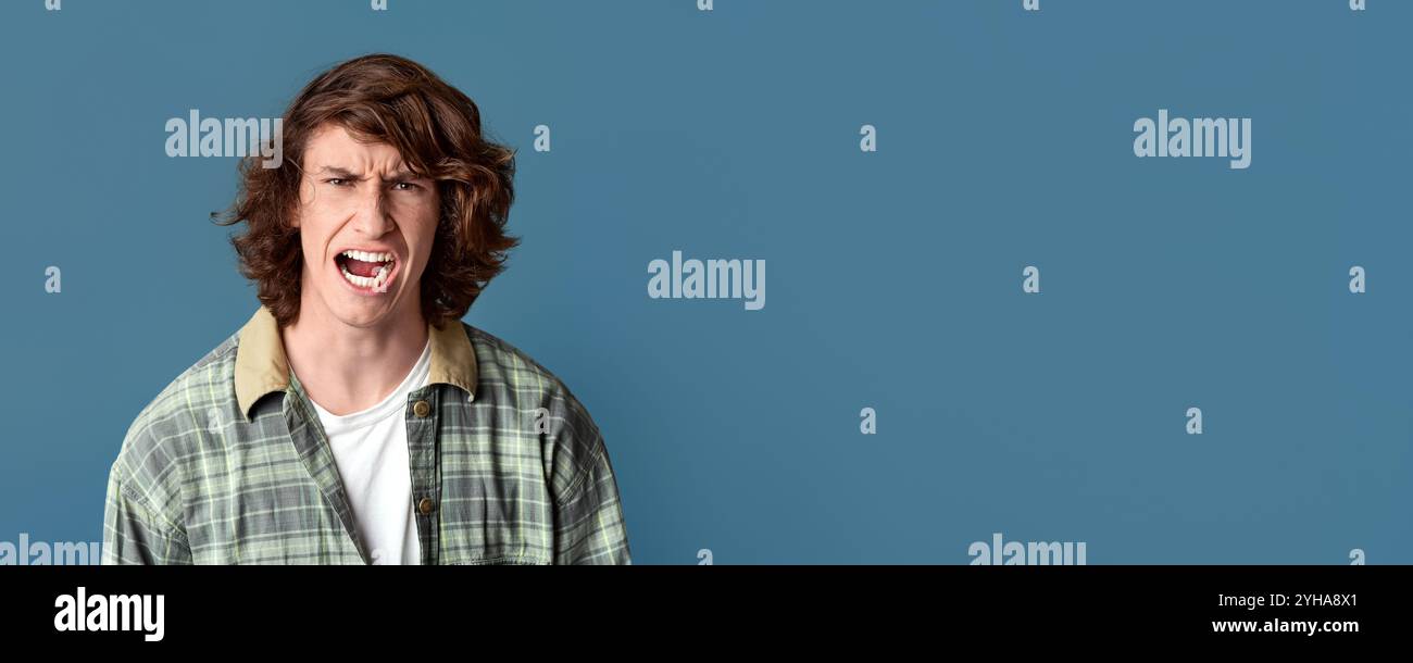 Expressing anger. Young guy with furious facial expression on color ...