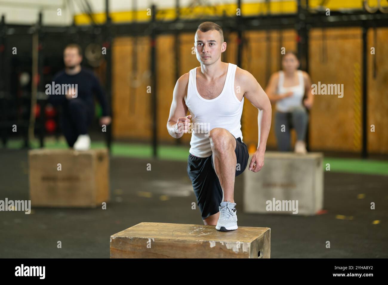 Sporty man performing box step-ups during high-intensity functional ...