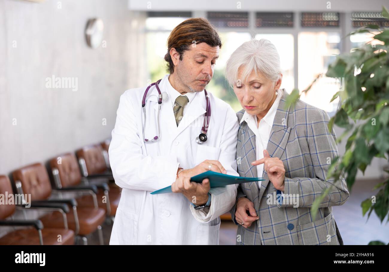 Attentive doctor prescribing tests to patient of clinic to check state ...