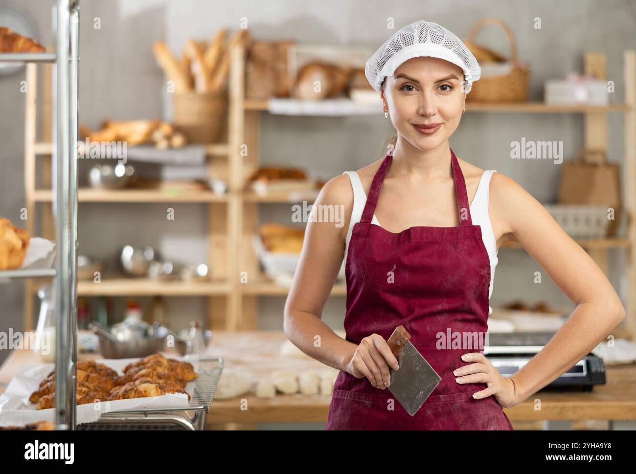 Portrait of successful young woman baker in apron smiling at camera ...