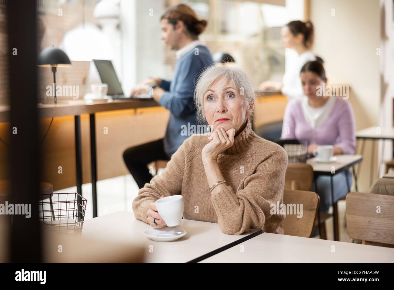 Sad elderly woman drinking coffee or tea at bar counter alone Stock ...