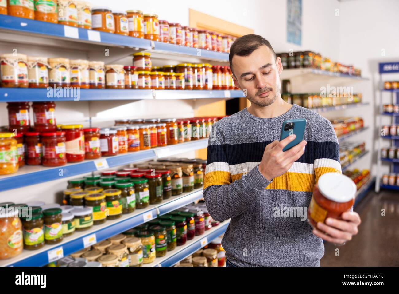 In Russian goods store, man choose jar of canned lecho and scan QR code ...