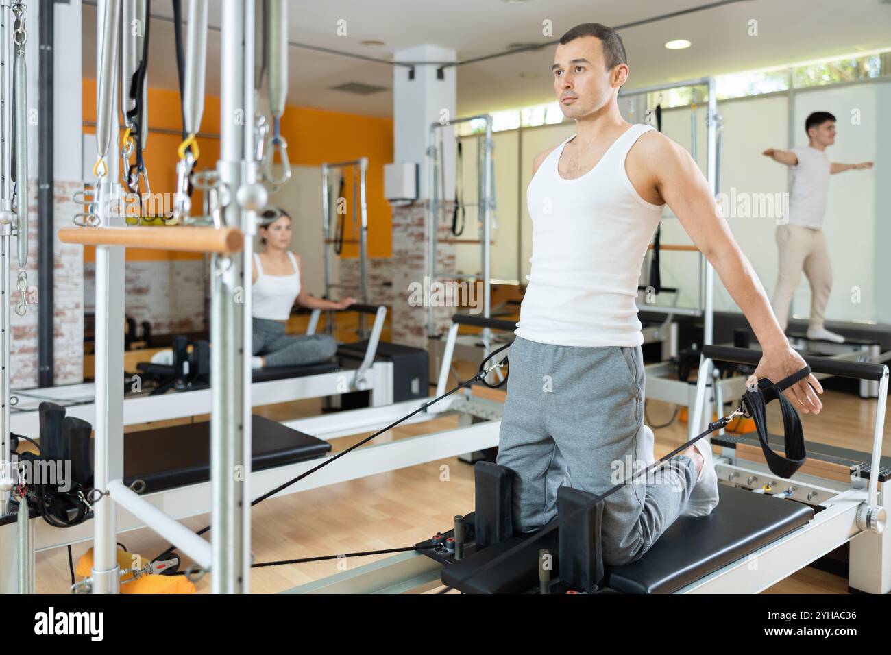 Man in gym with help of rope reformer performs exercises to strengthen ...