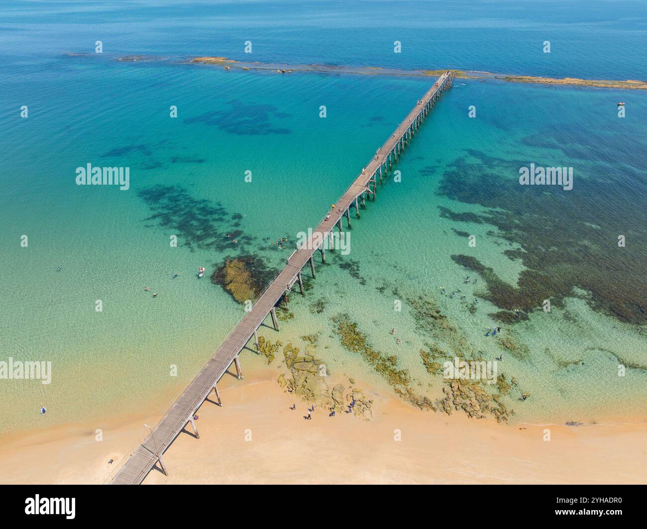 Aerial view of a long coastal jetty going out to a rocky reef in a ...