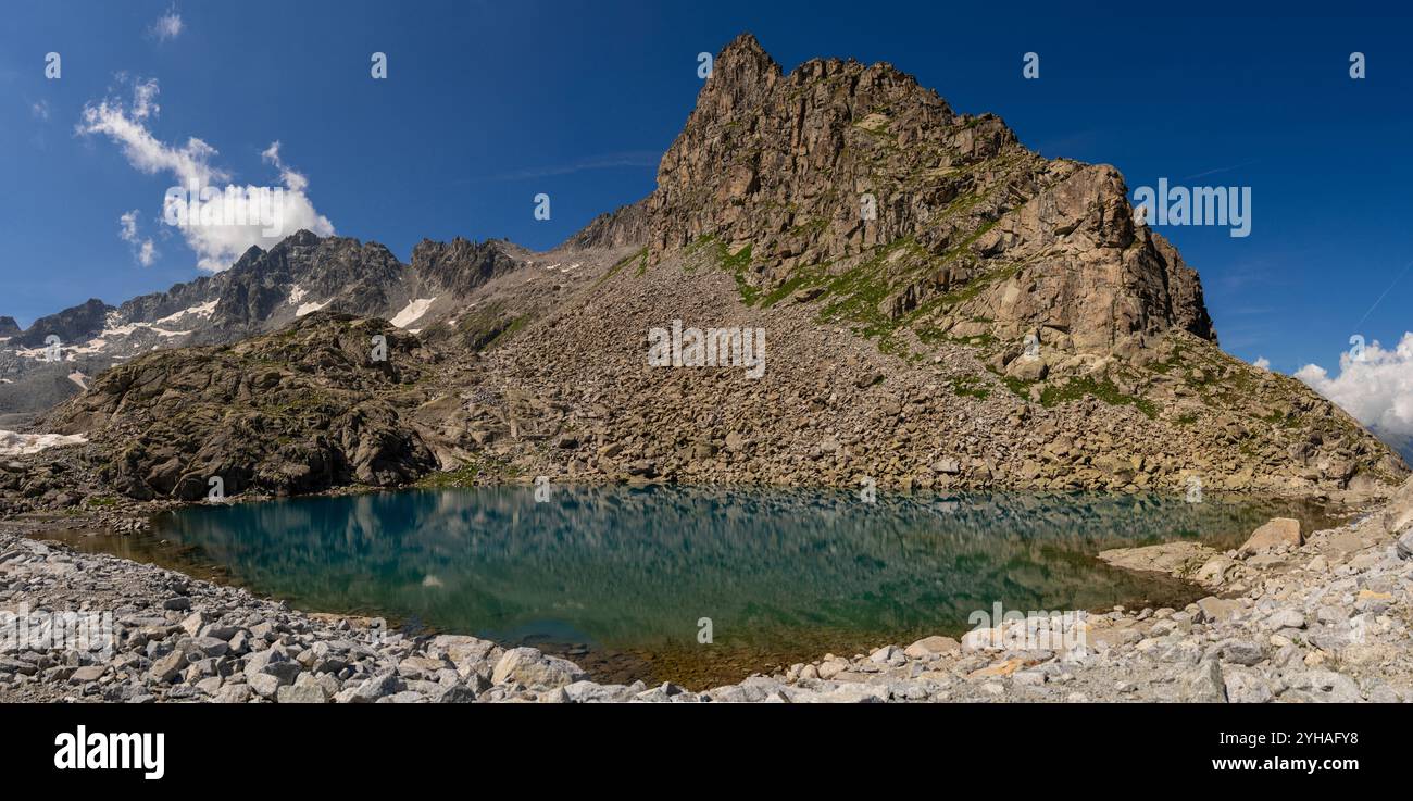 Clear mountain lake reflecting rugged cliffs and snow capped peaks in ...