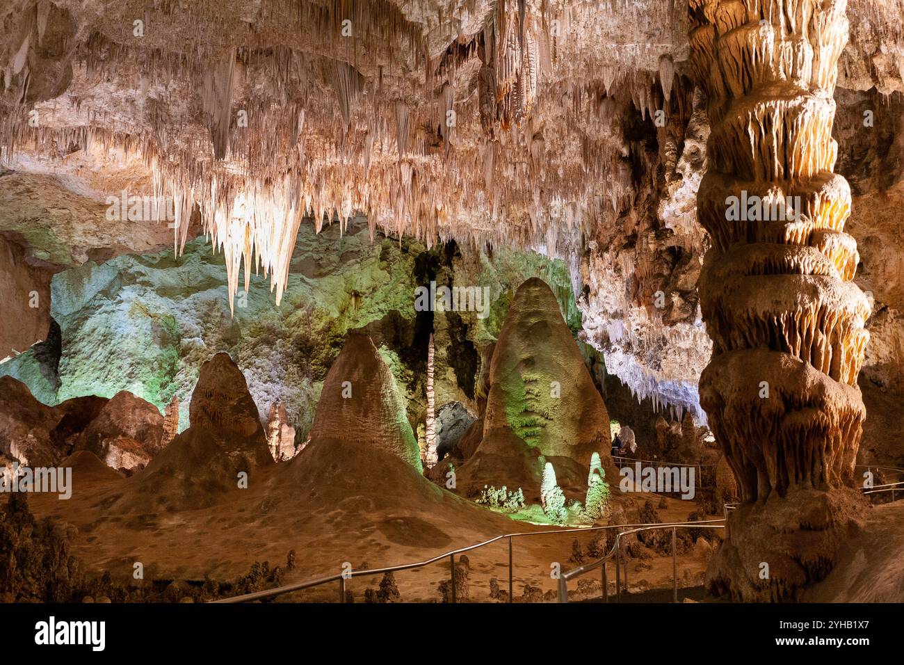 A large chandelier hanging from the cave ceiling with stalagtites above ...