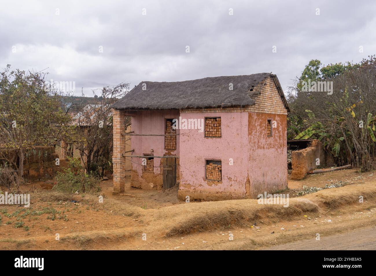 A traditional Malagasy house with a thatched roof and mud brick walls ...