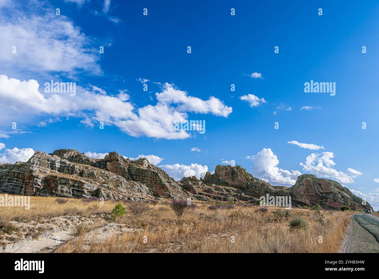 Dramatic layered sandstone cliffs rise above dry savanna grassland ...