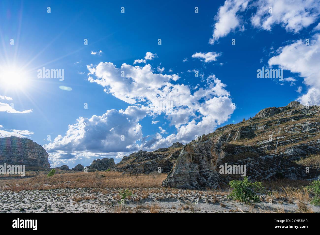 Dramatic layered sandstone cliffs rise above dry savanna grassland ...