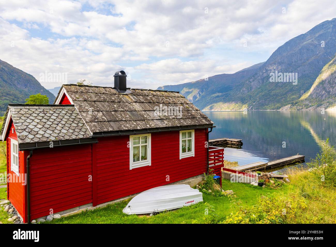 Traditional red norwegian home on the shore of Eid fjord which is an ...