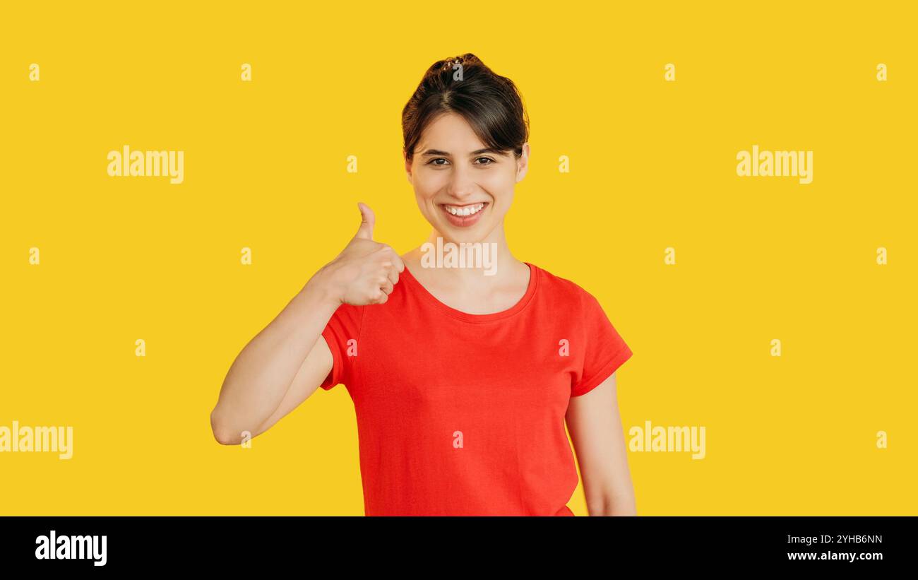 Like gesture. Cheerful woman in red smiling approving with thumb up ...