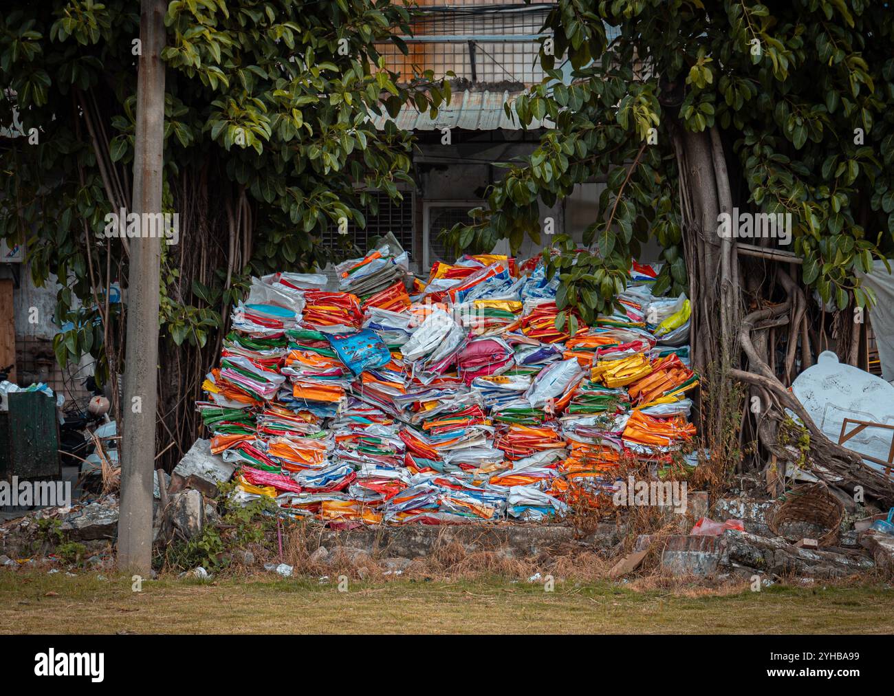A large pile of colorful discarded plastic bags stacked in an outdoor ...