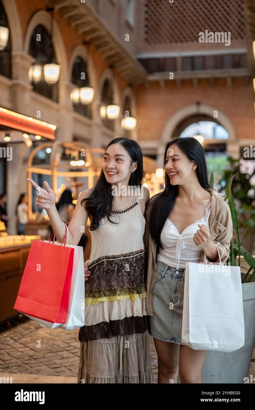 Two charming and carefree Asian women enjoying shopping together at a ...