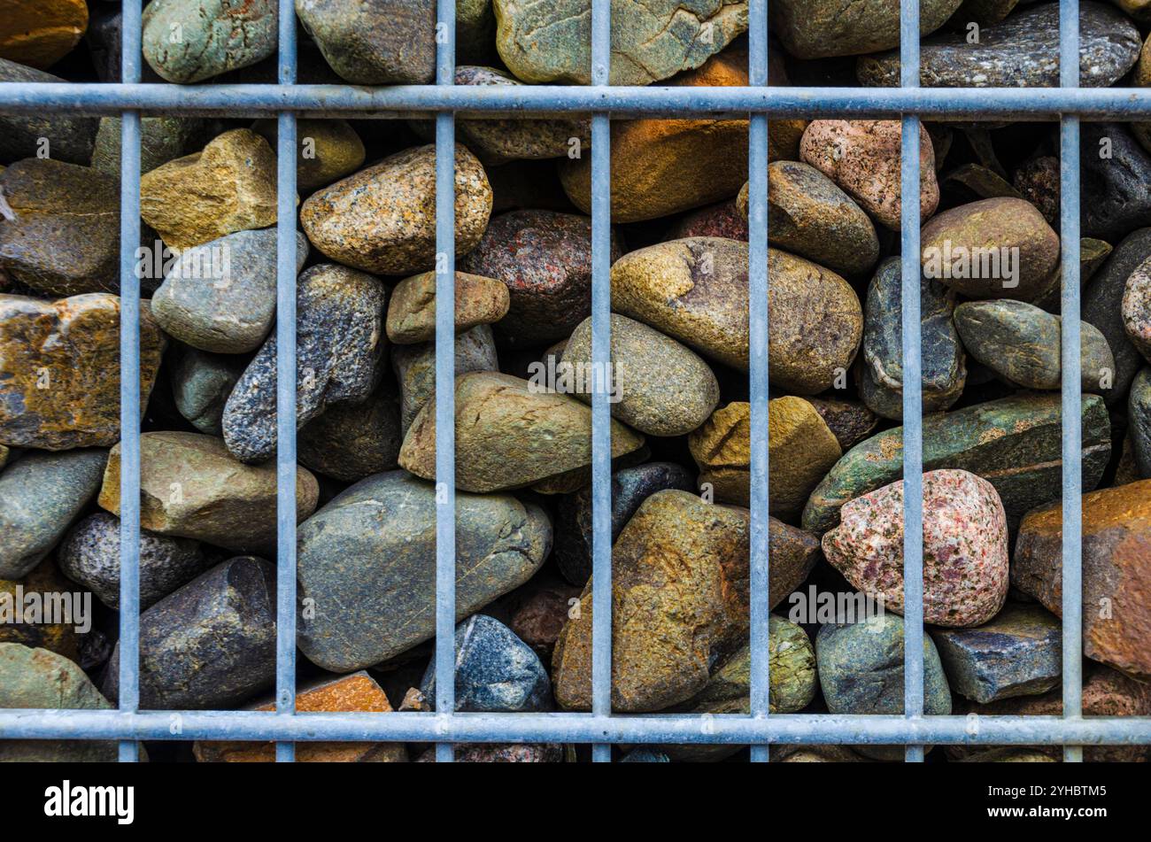 Close up of stones encased in a wire casing forming a retaining wall in ...