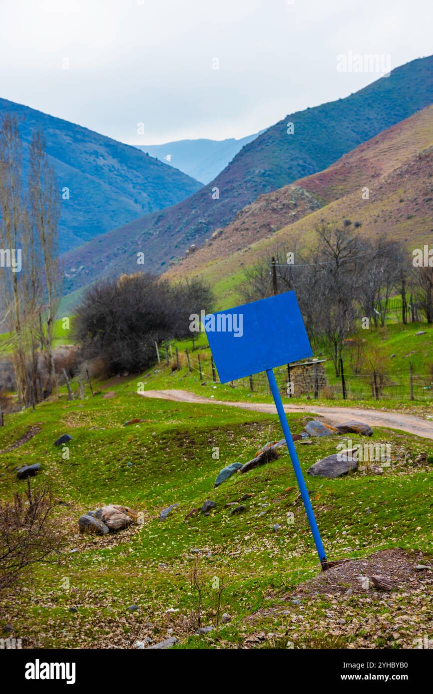 a crooked blank blue sign on a steel pole at the entrance to mountain ...