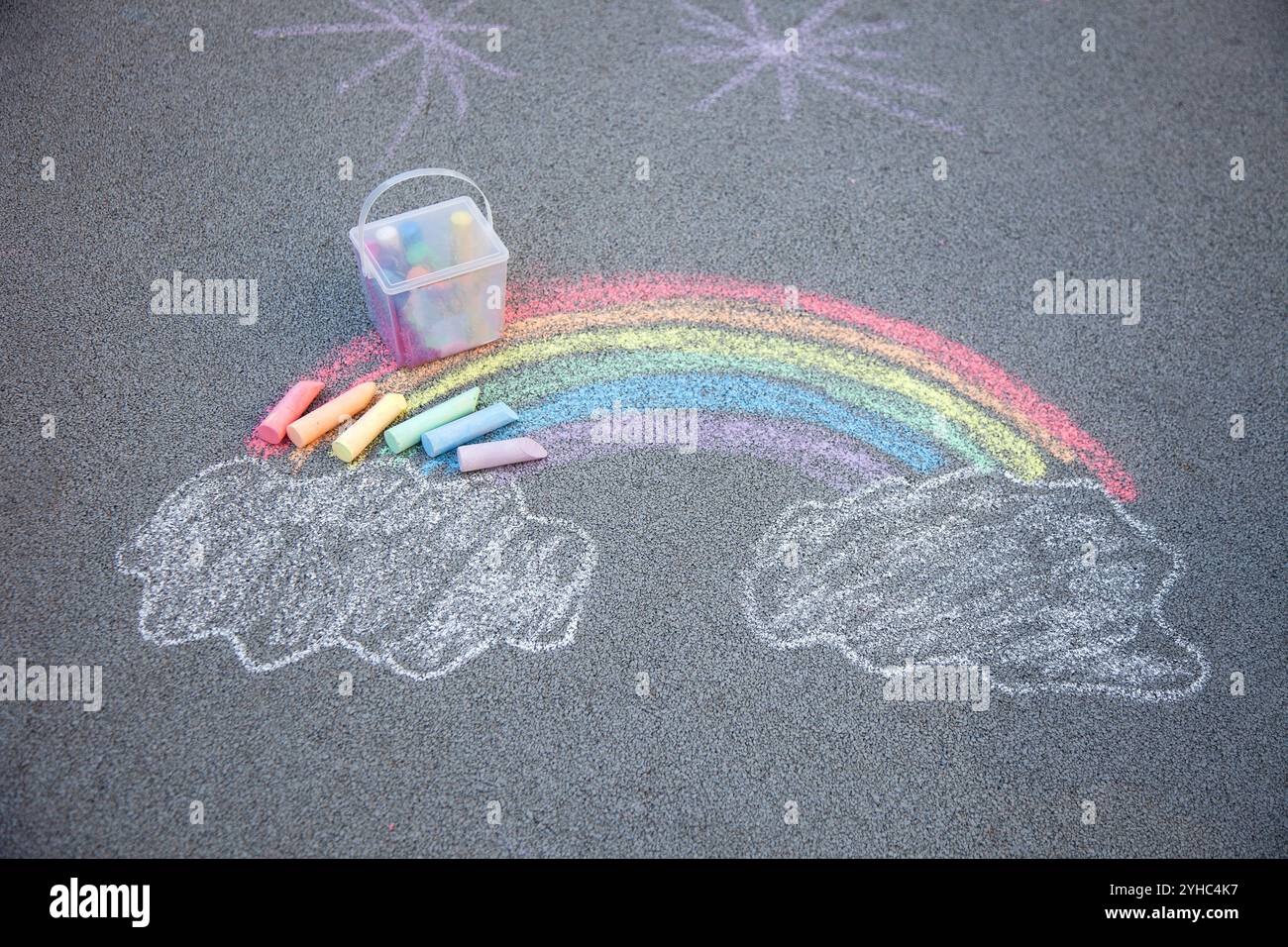 Sidewalk chalk drawing. A rainbow and clouds sky painted on the asphalt ...