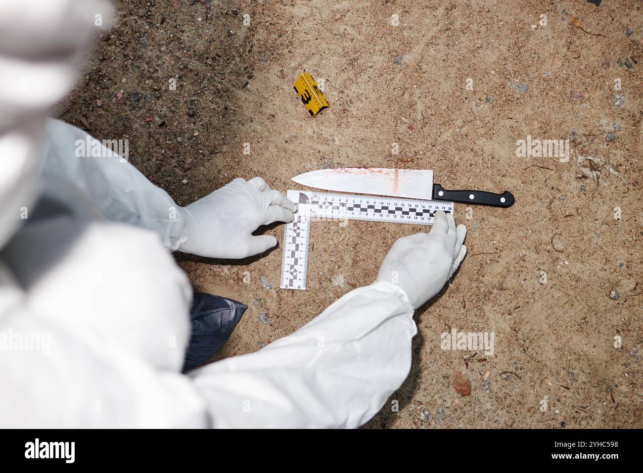 Top view closeup of forensic investigator putting measuring tape next ...