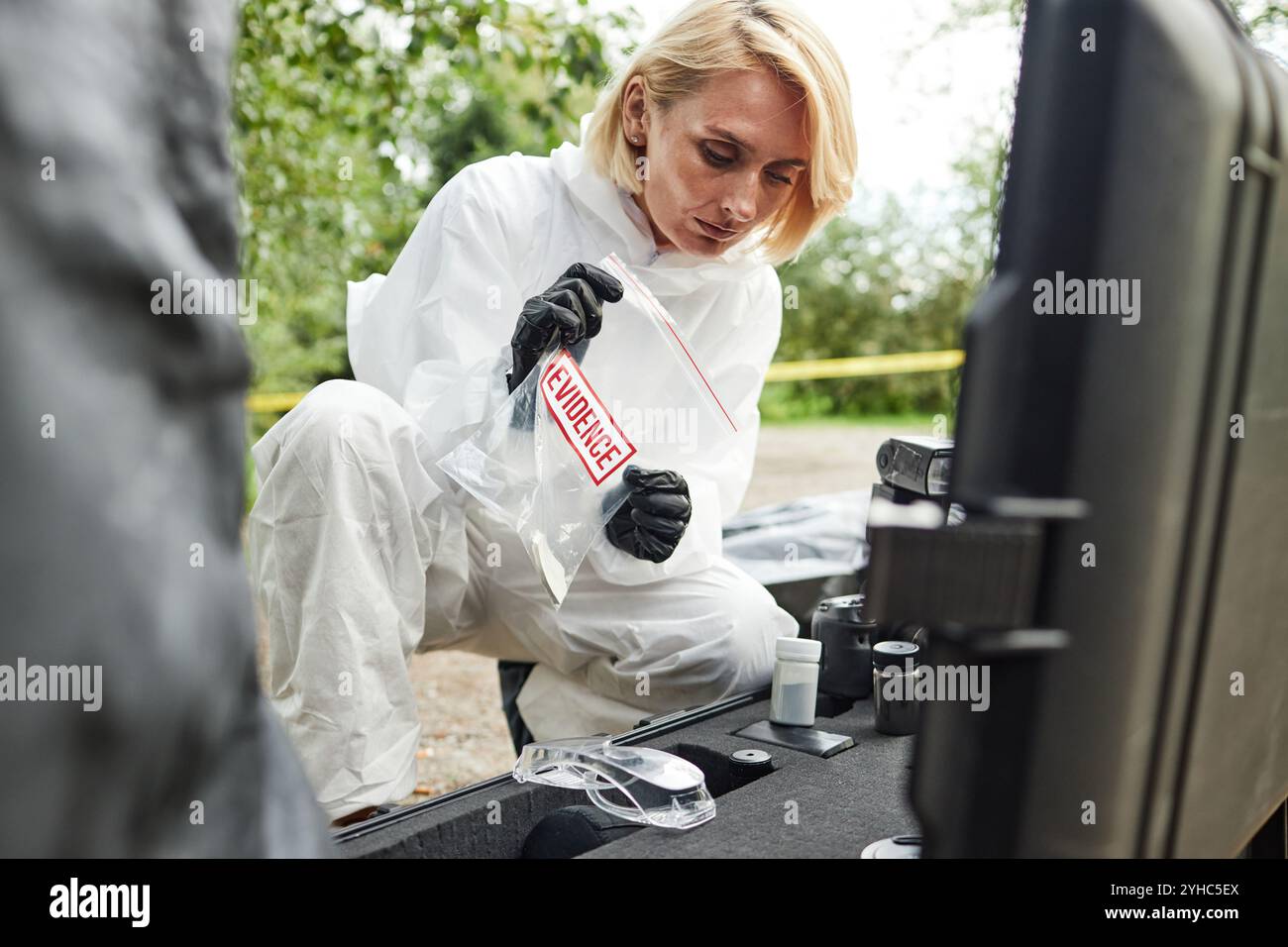 Side view of female forensic scientist wearing hazmat suit and using ...