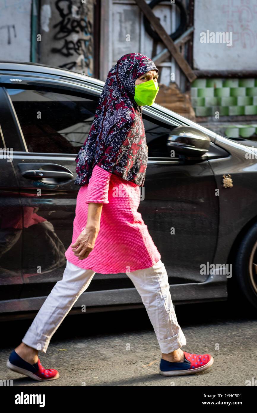 A Filipino Muslim lady, wearing a covid mask makes her way down a ...