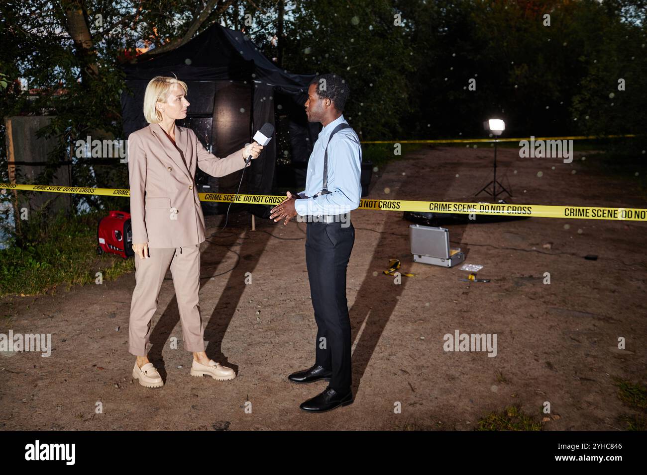 Full length portrait of female reporter interviewing police officer at ...