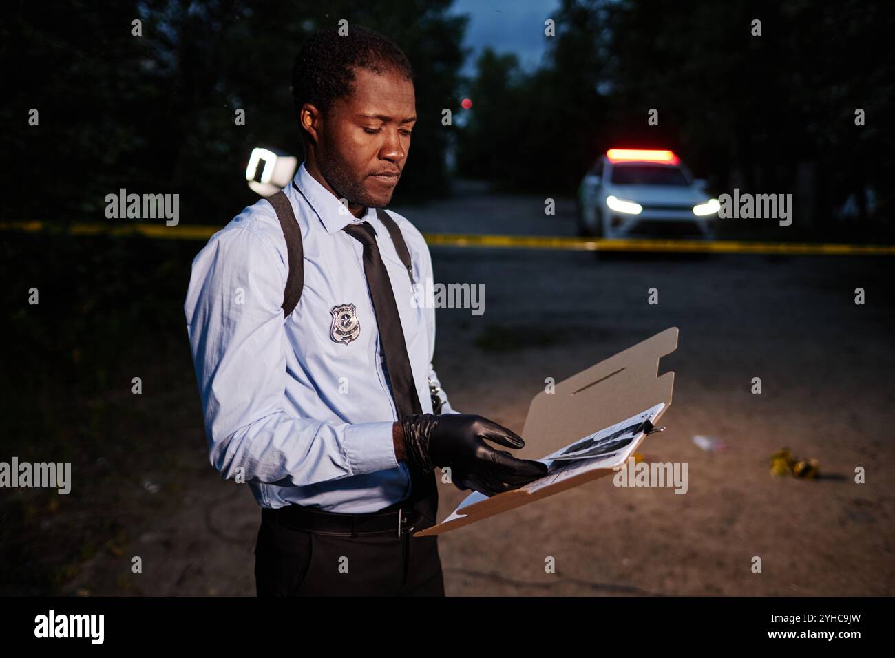 Waist up side view of African American police investigator reading ...