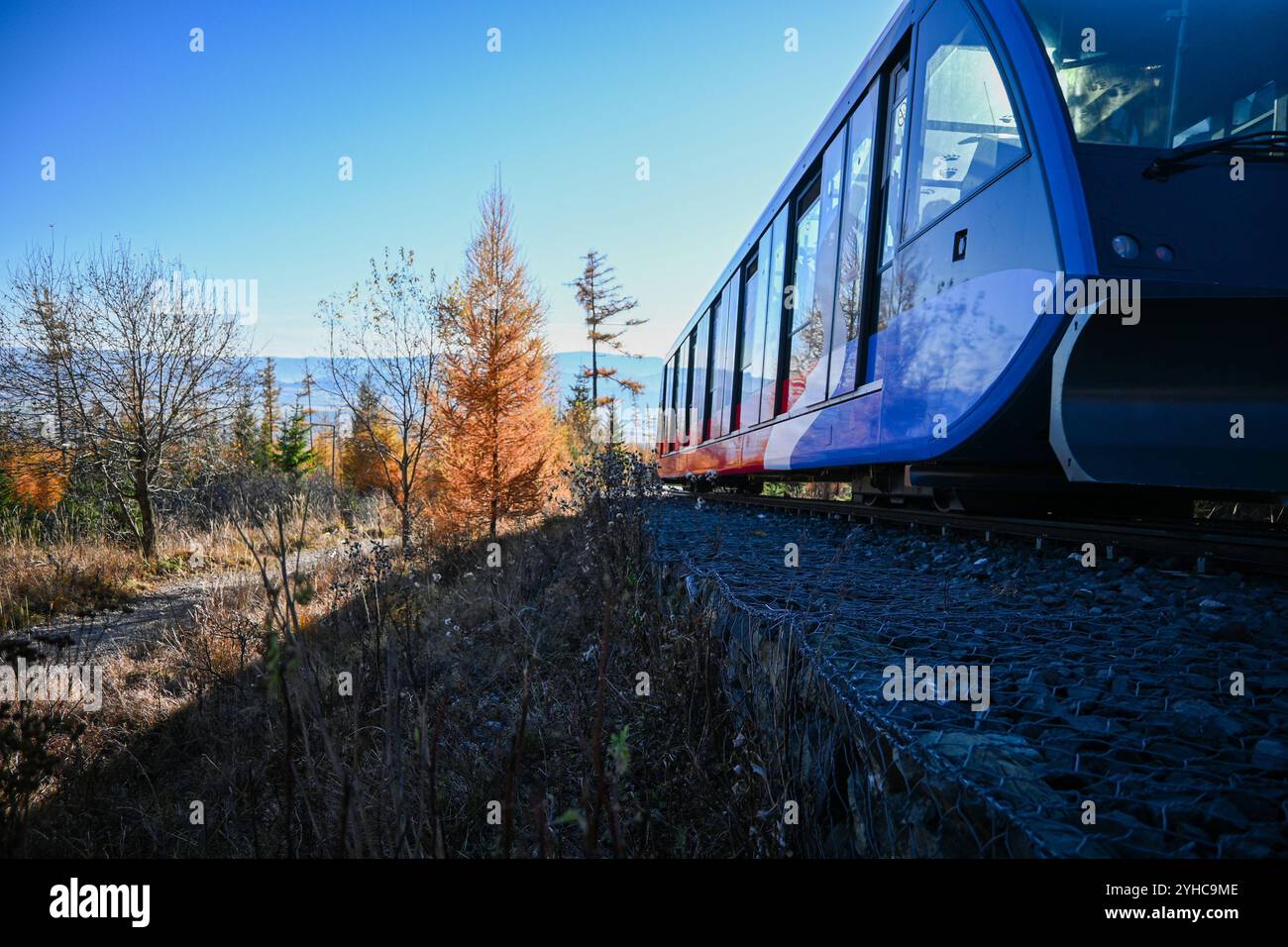 Modern red funicular is climbing a mountain slope, surrounded by ...