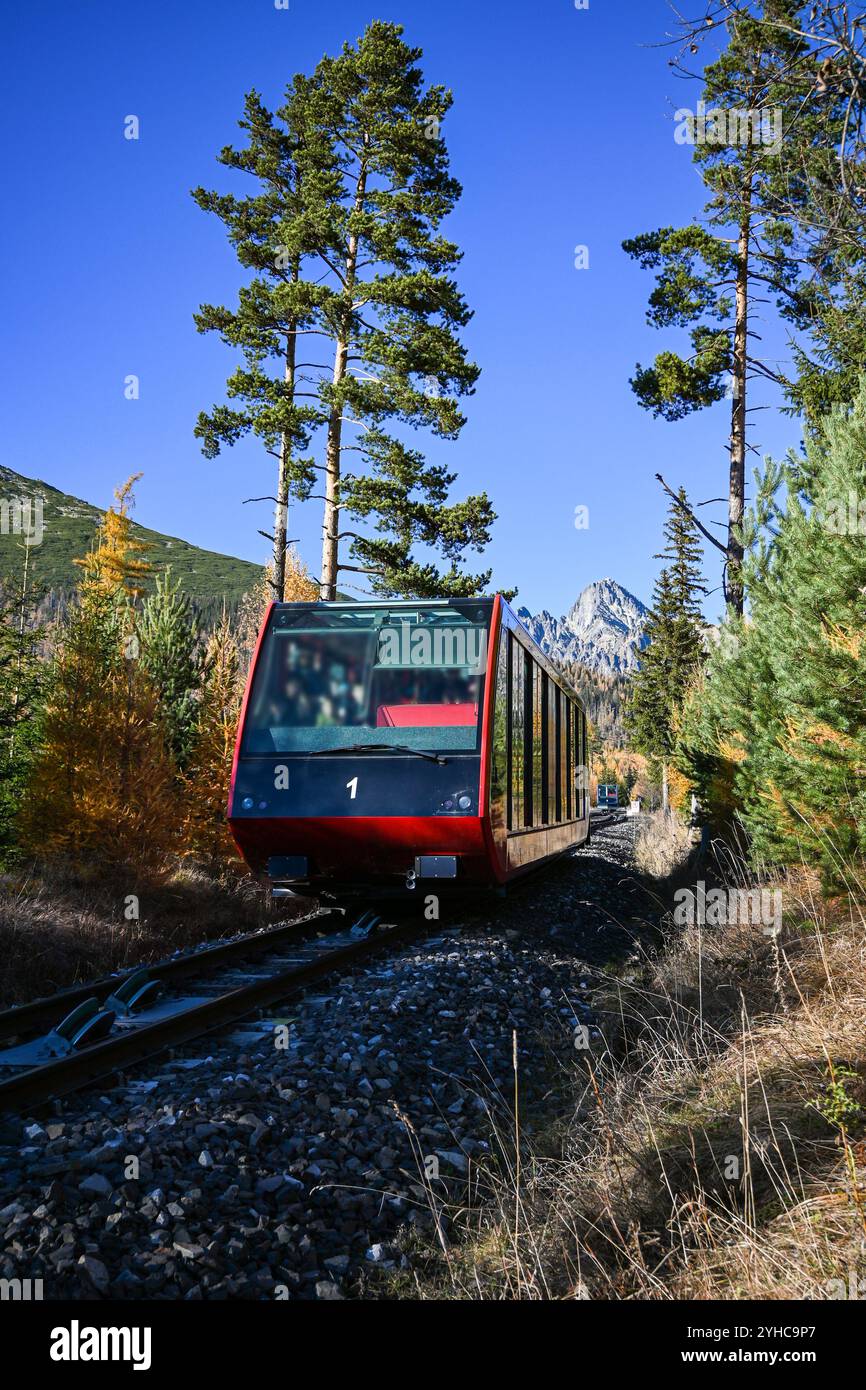 Modern red funicular is climbing a mountain slope, surrounded by ...