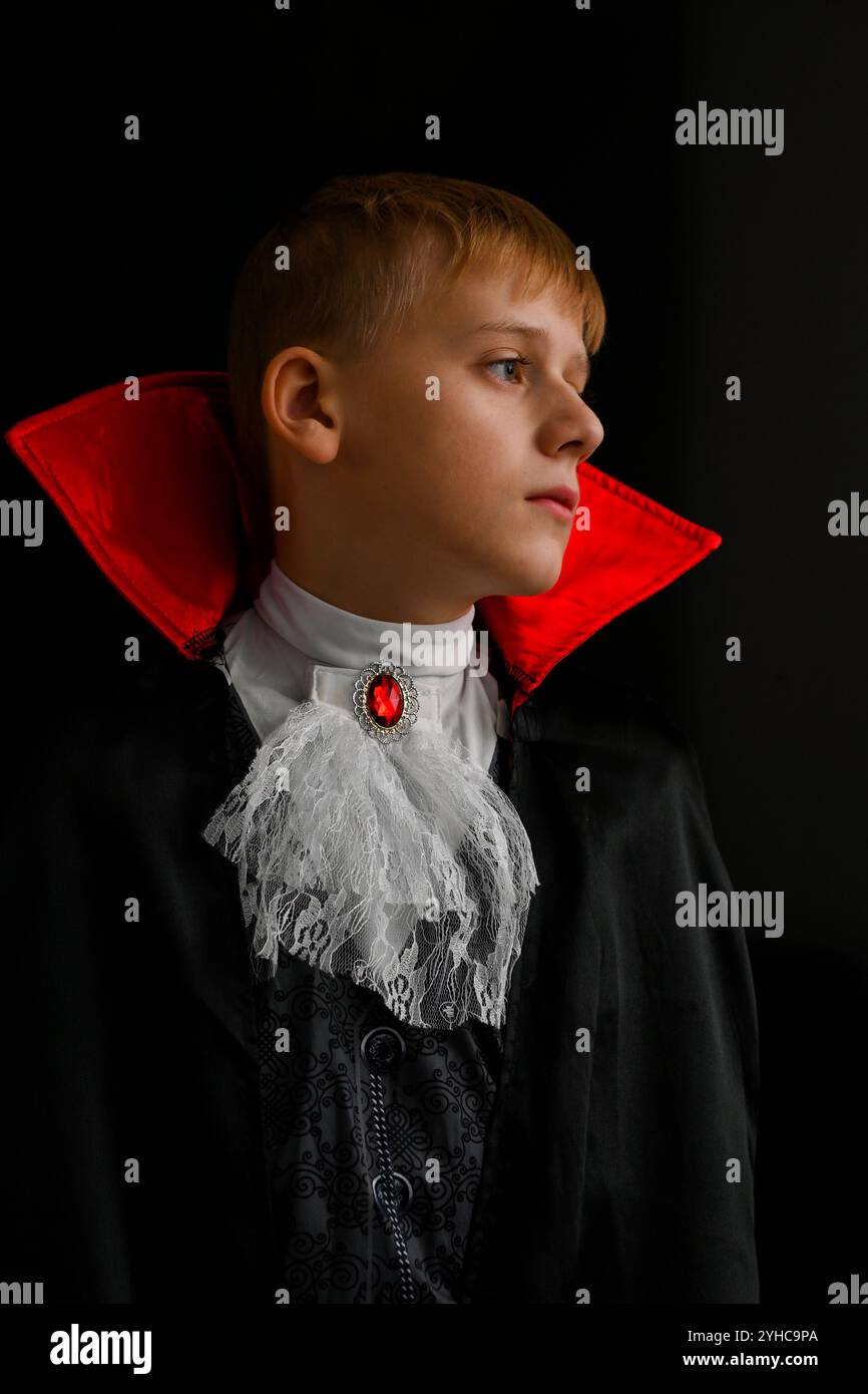 Portrait of a boy wearing a vampire costume posing on a black ...