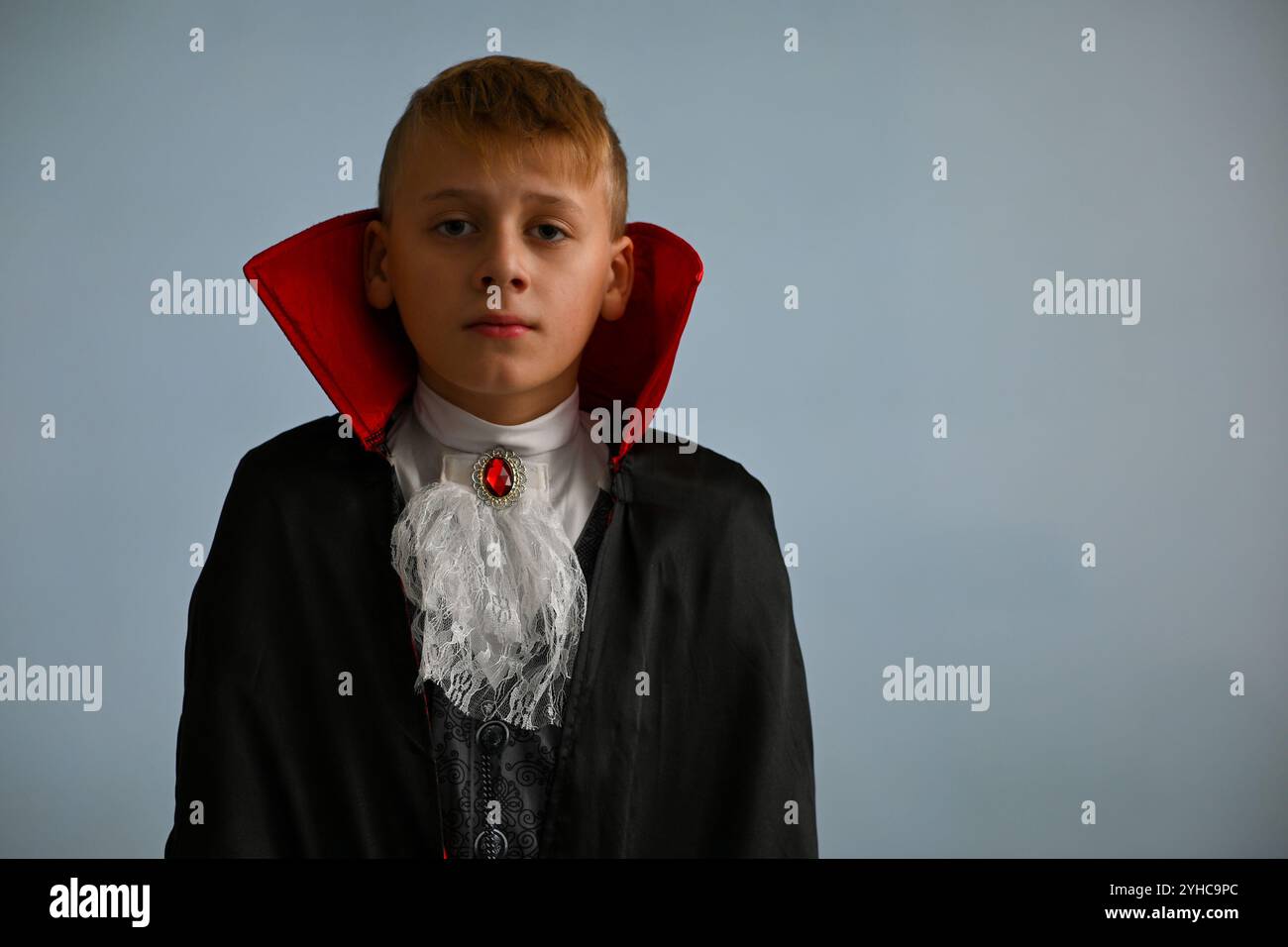 Portrait of a boy wearing a vampire costume with a red and black cape ...