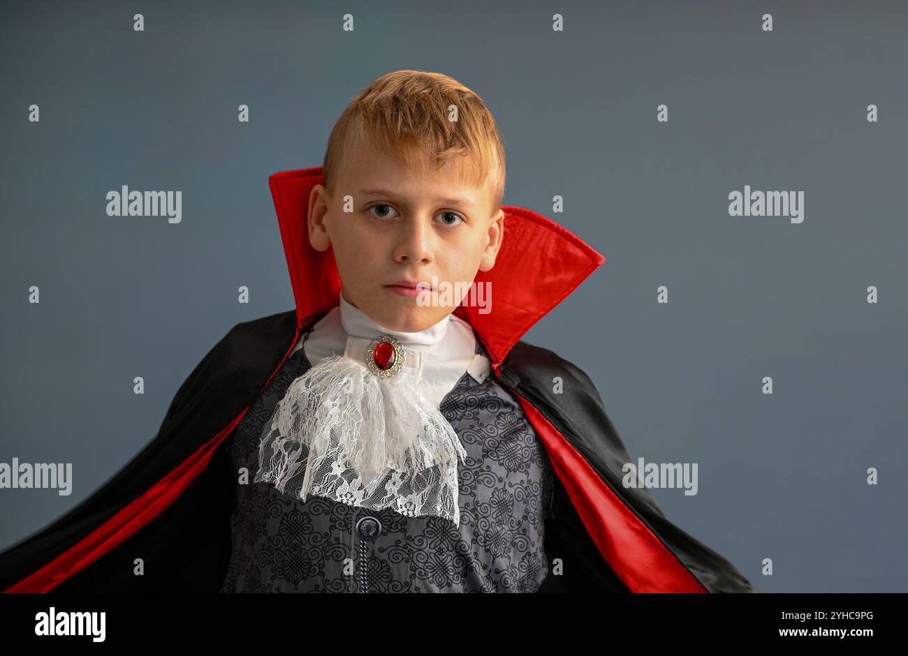 Portrait of a boy wearing a vampire costume with a red and black cape ...