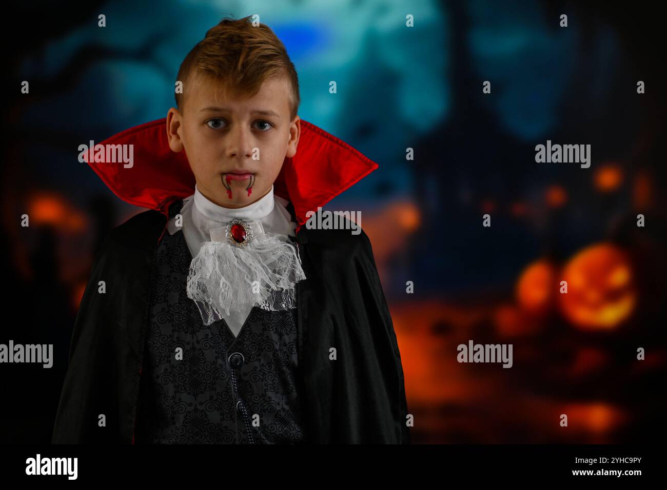 Child dressed as a vampire posing in front of a blurred background with ...