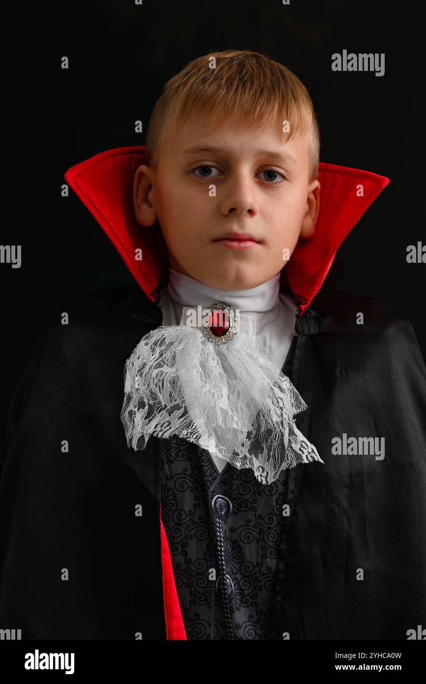 Portrait of a boy wearing a vampire costume posing on a black ...