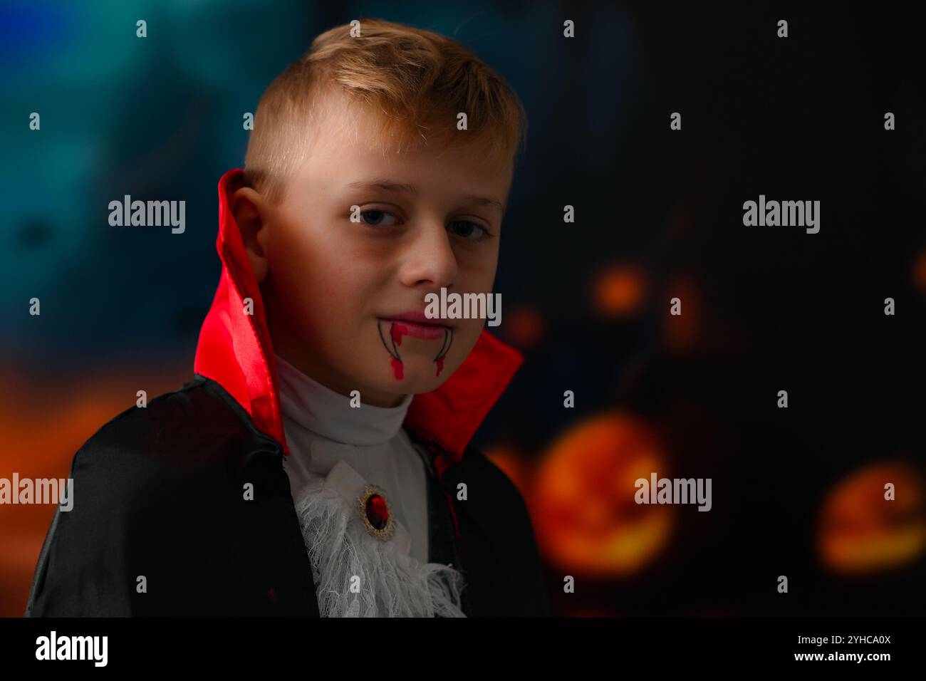 Child dressed as a vampire posing in front of a blurred background with ...