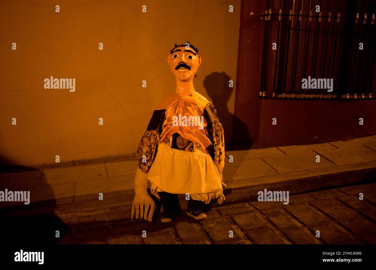 A boy standing inside a giant paper mache puppet rests after dancing in ...