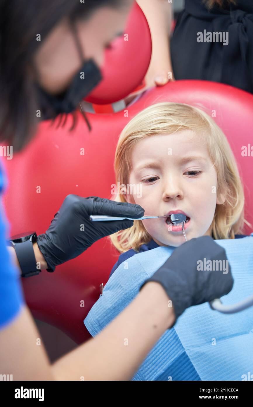 Close-up of cute elementary-aged boy sitting in dentist chair, opening ...