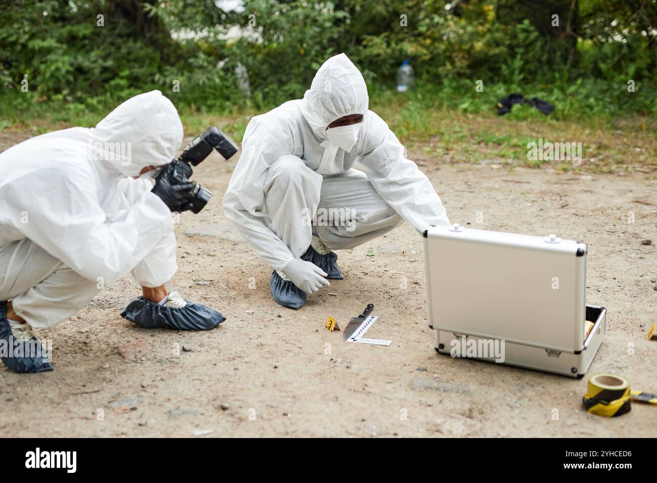 Two people wearing protective suits working at crime scene taking ...