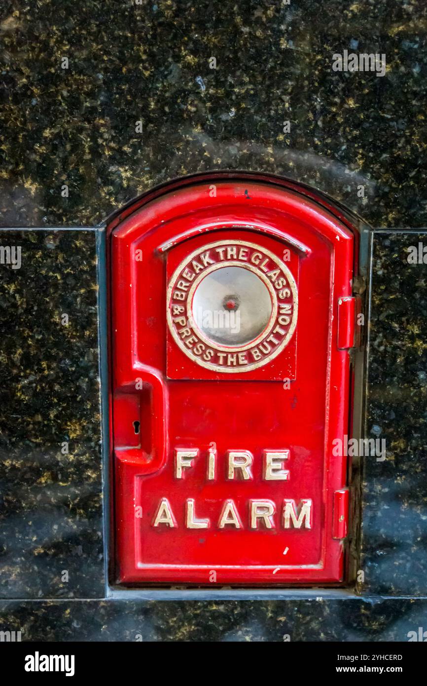 Old red fire alarm box mounted on a granite wall with instructions for ...