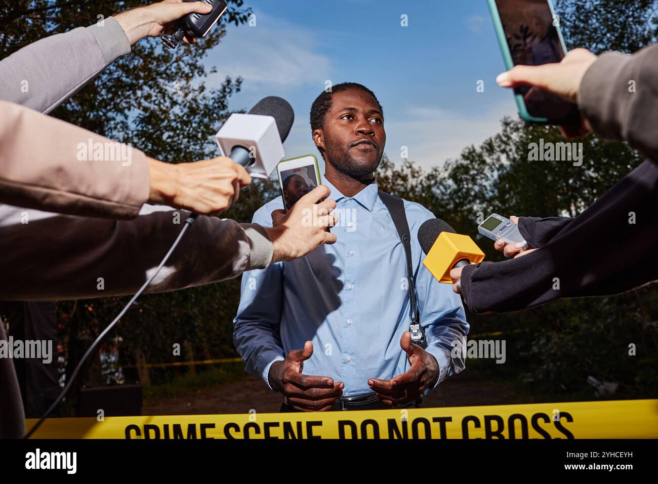 Low angle portrait of young Black police officer giving statement at ...